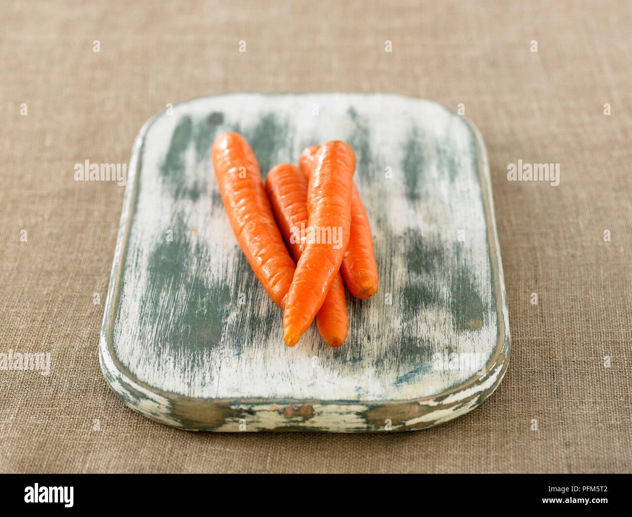 Four whole carrots on chopping board Stock Photo - Alamy