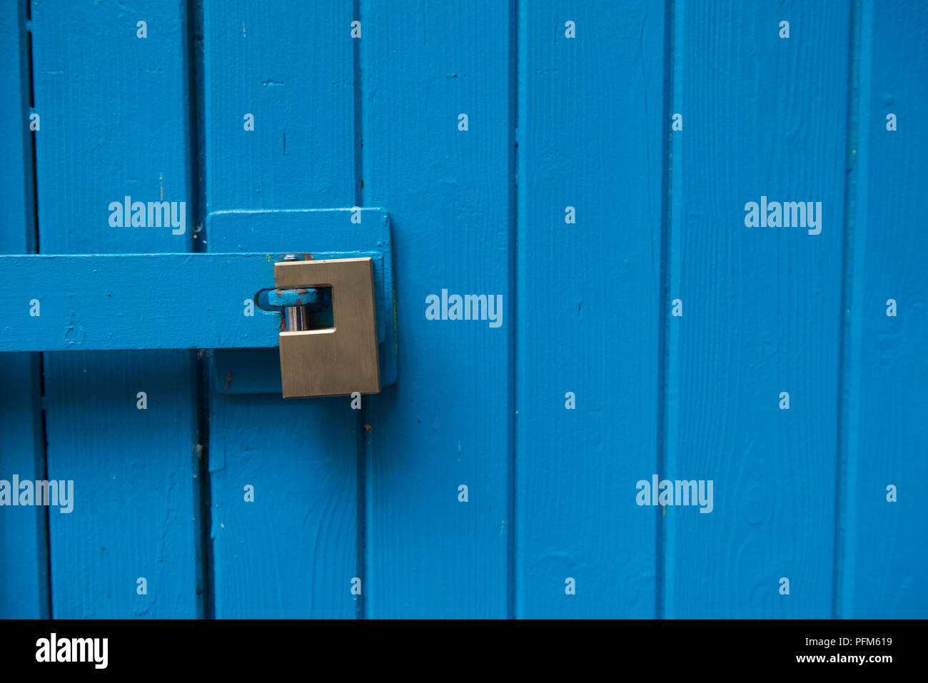 Blue wooden doors locked with modern yellow lock Stock Photo - Alamy