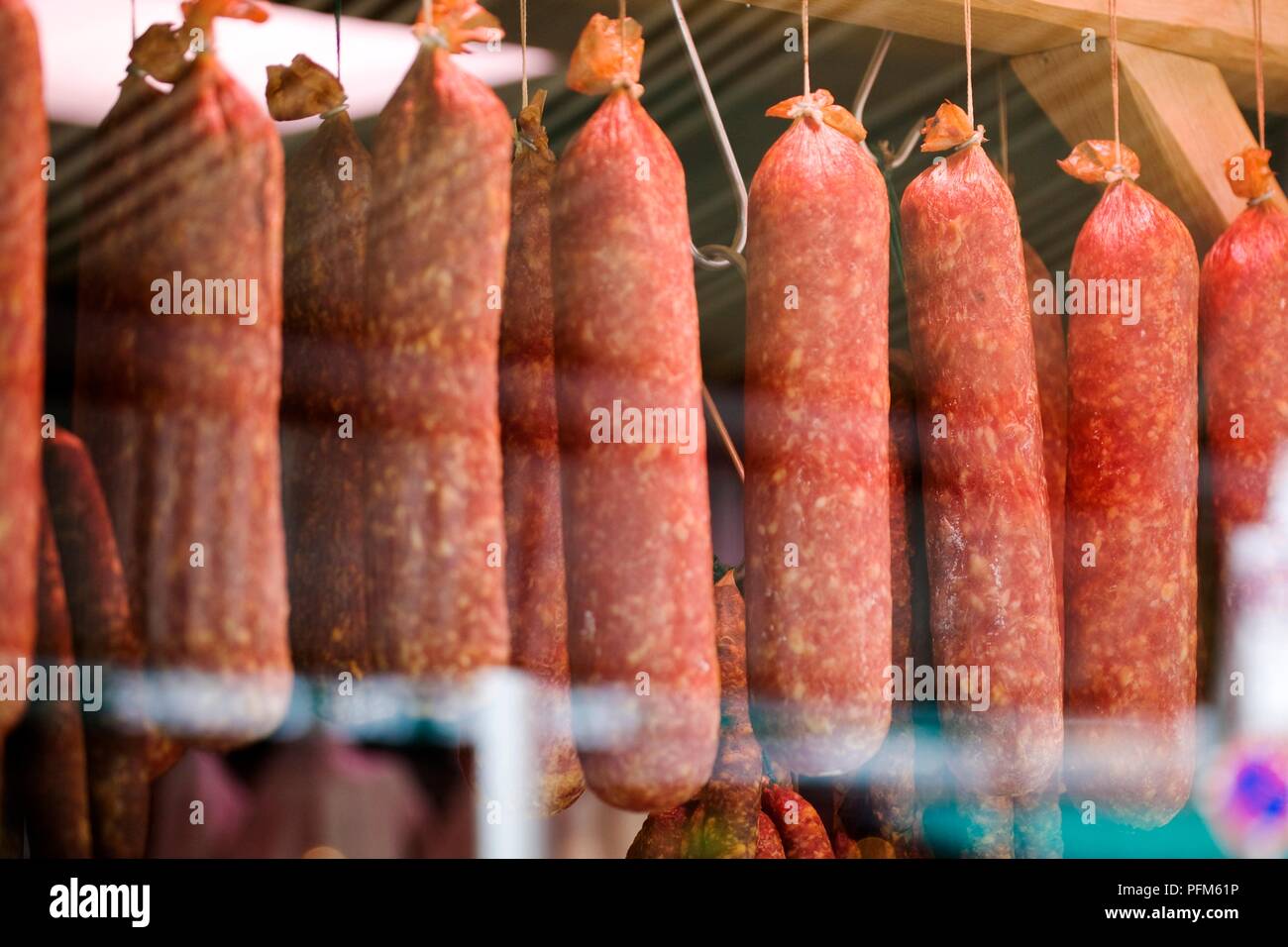 Cured meats hanging on hooks in window Stock Photo - Alamy