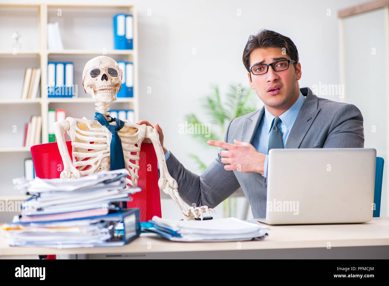 Businessman working with skeleton in office Stock Photo - Alamy