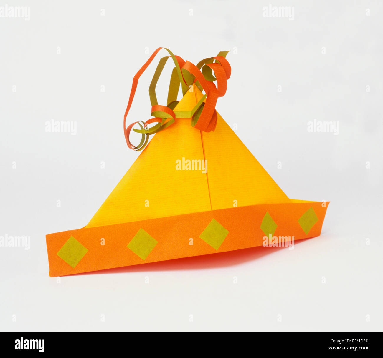 Yellow and orange paper hat with streamers on top Stock Photo - Alamy