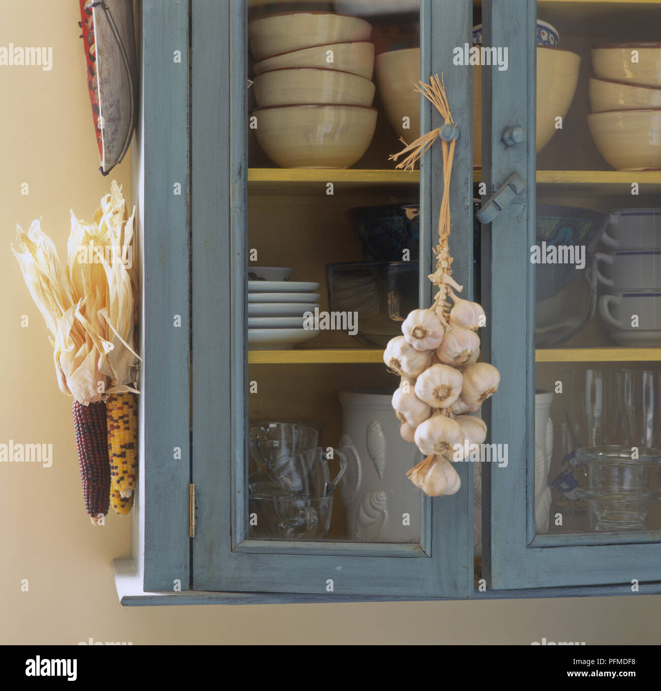 Window-fronted old cupboard with garlic cloves hanging on the door ...