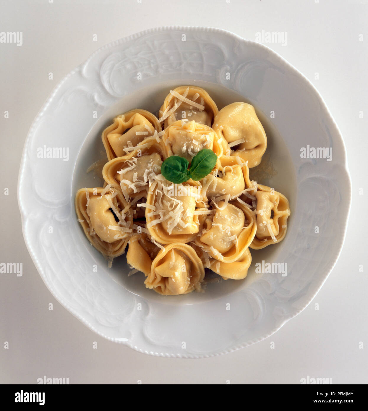 Bowl of Tortelloni with grated cheese, garnished with basil leaves ...