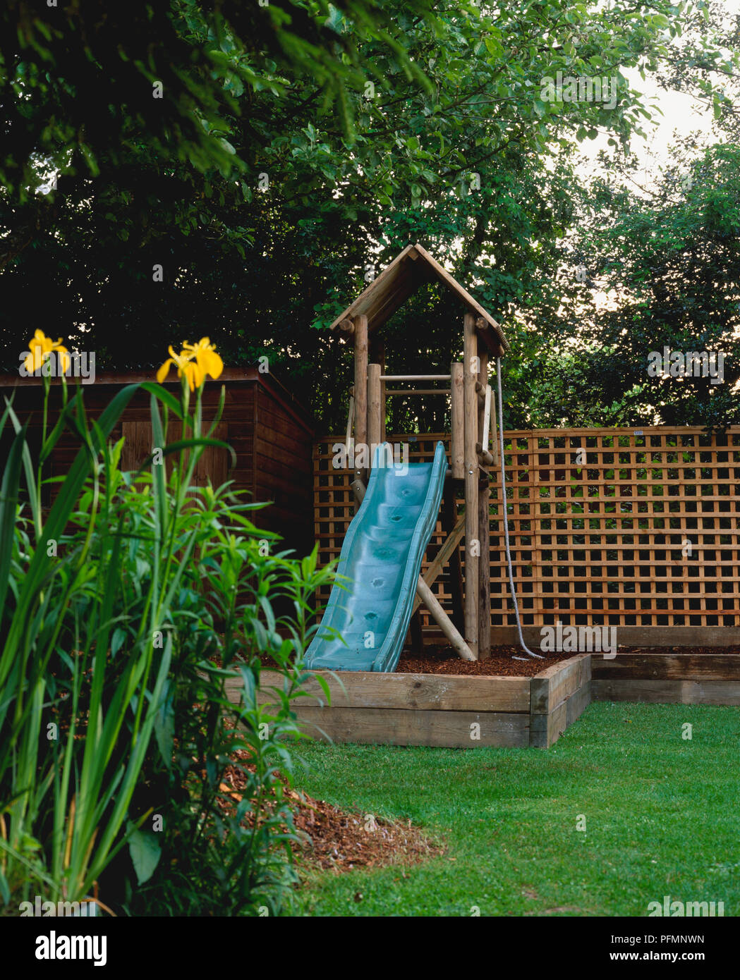 Timber climbing tower and slide set into a floor of bark chips, garden ...
