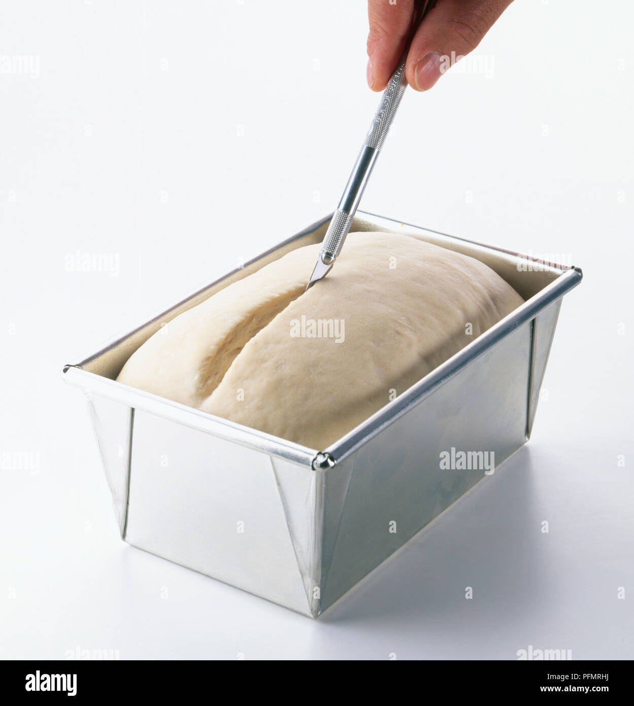 Hand using scalpel to make slash in risen bread dough, close-up Stock ...