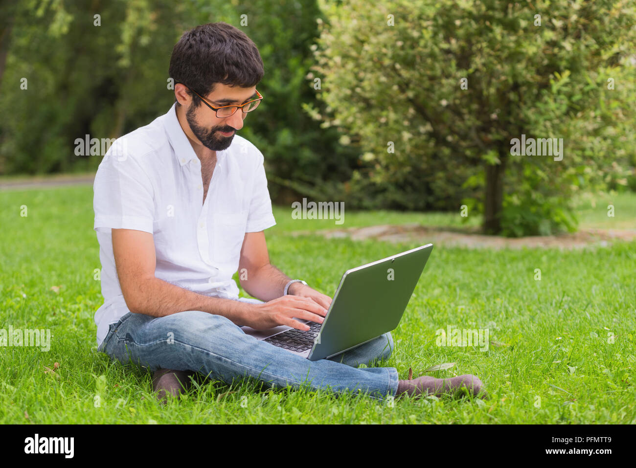 Handsome man sitting on the green grass in park hi-res stock ...