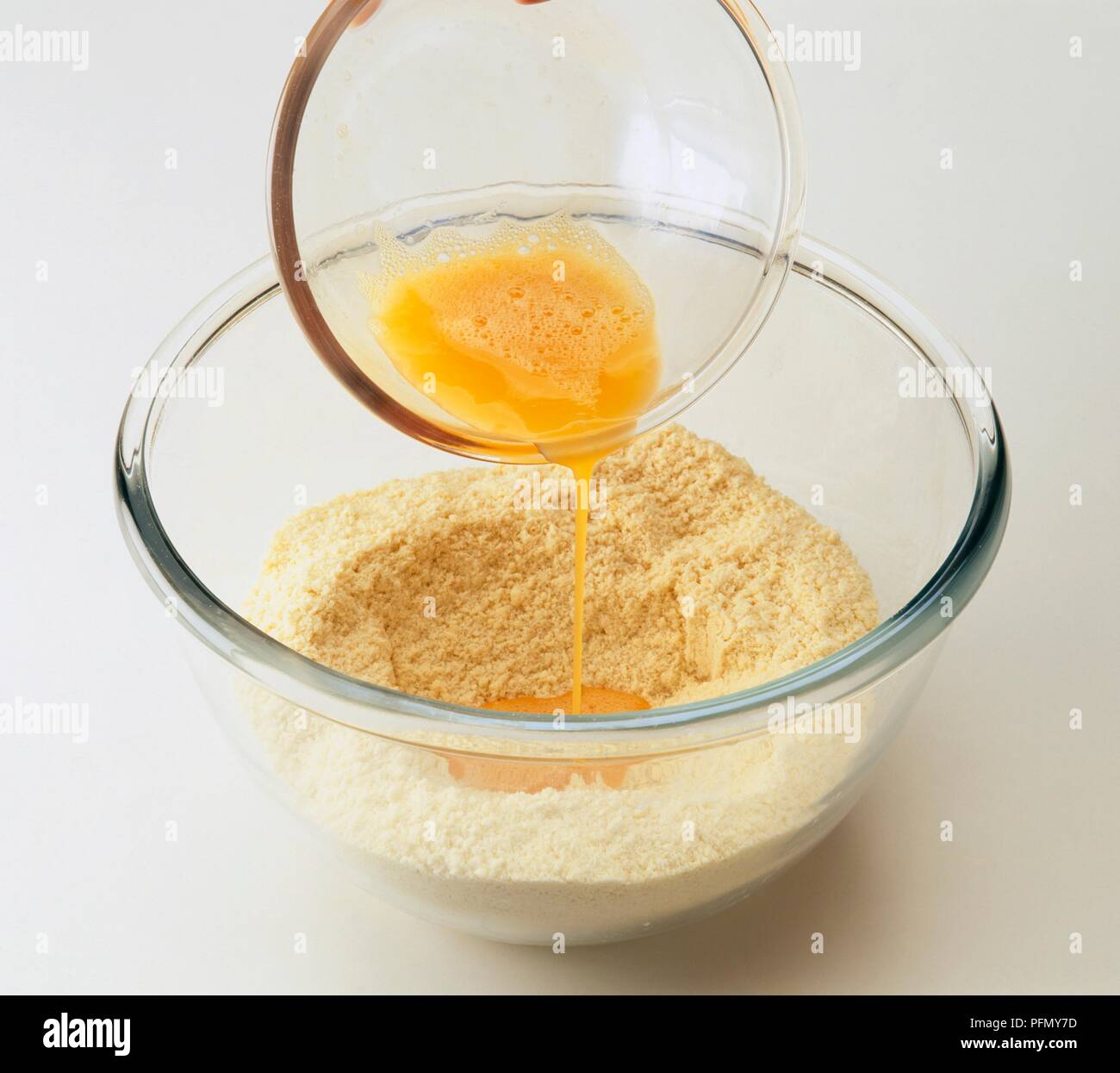 Pouring egg yoke into pastry mix in glass mixing bowl Stock Photo - Alamy