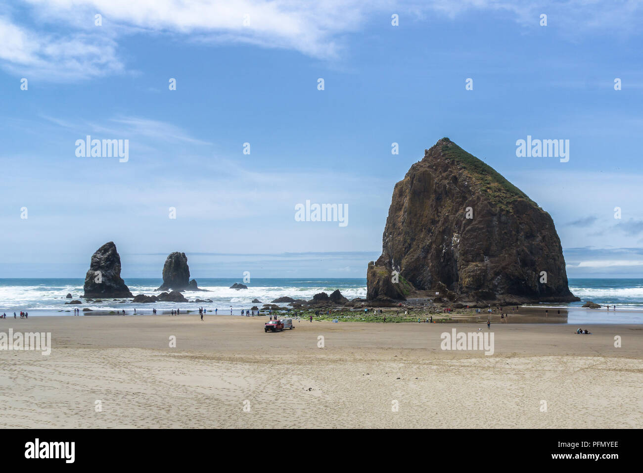 The Haystack Rock Wildlife Refuge with people enjoying tidepools at low ...