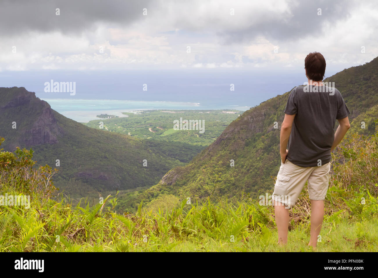 A man enjoys a view of the of the mountains and the ocean at the island ...