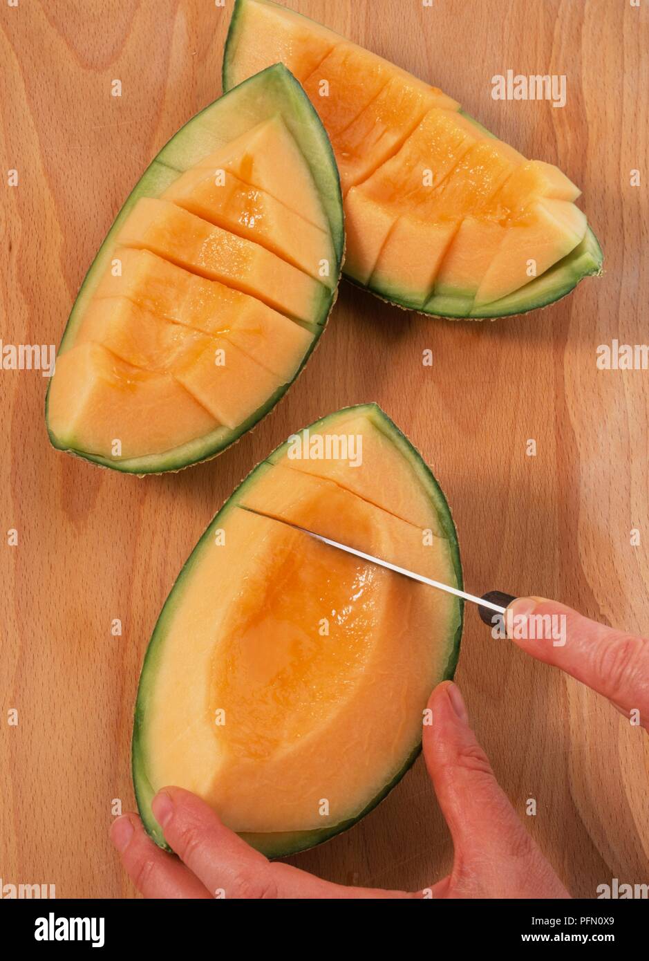 Using kitchen knife to slice melon on chopping board Stock Photo - Alamy