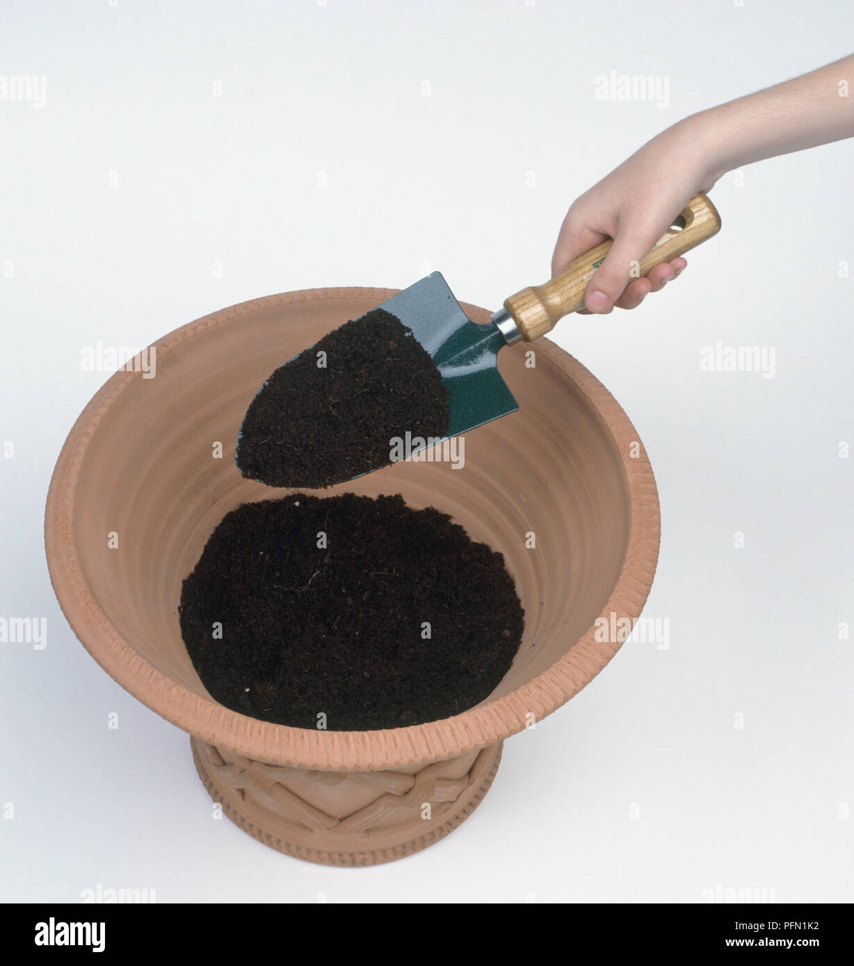 Hand filling plant pot with compost, using trowel, close-up Stock Photo ...