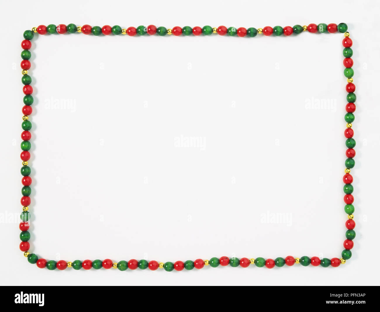 Red and green beads arranged in rectangle with small toy figure in ...