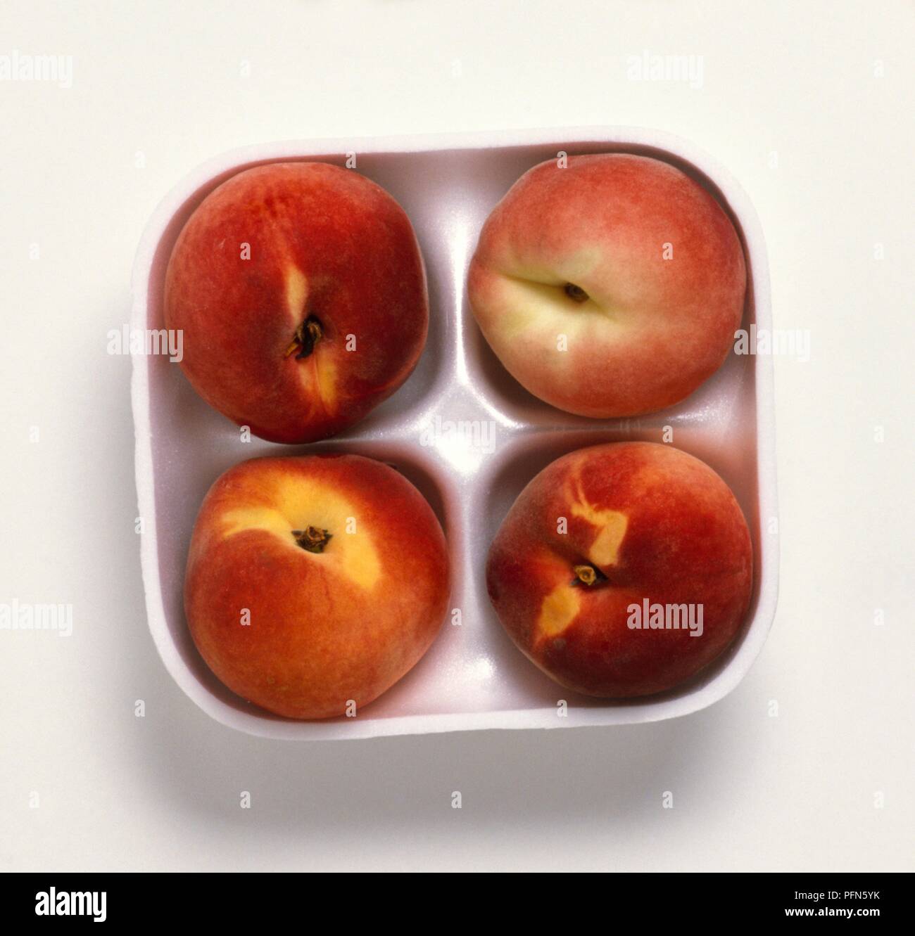 Four peaches in polystyrene packaging Stock Photo - Alamy