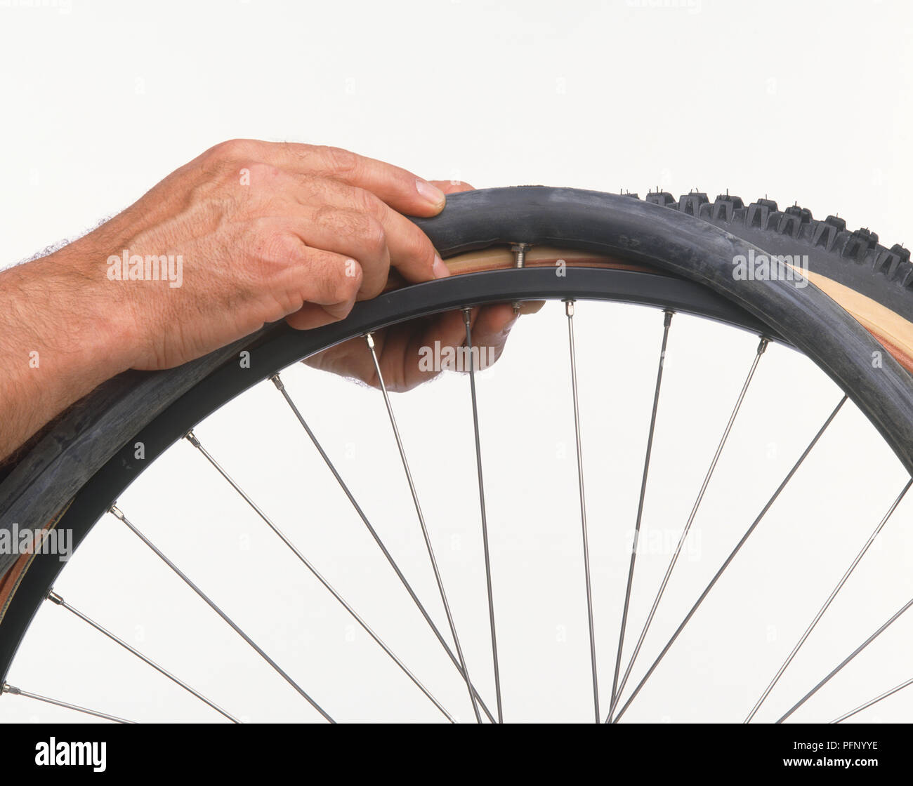 Using hands to attach inner tube to bicycle wheel Stock Photo - Alamy