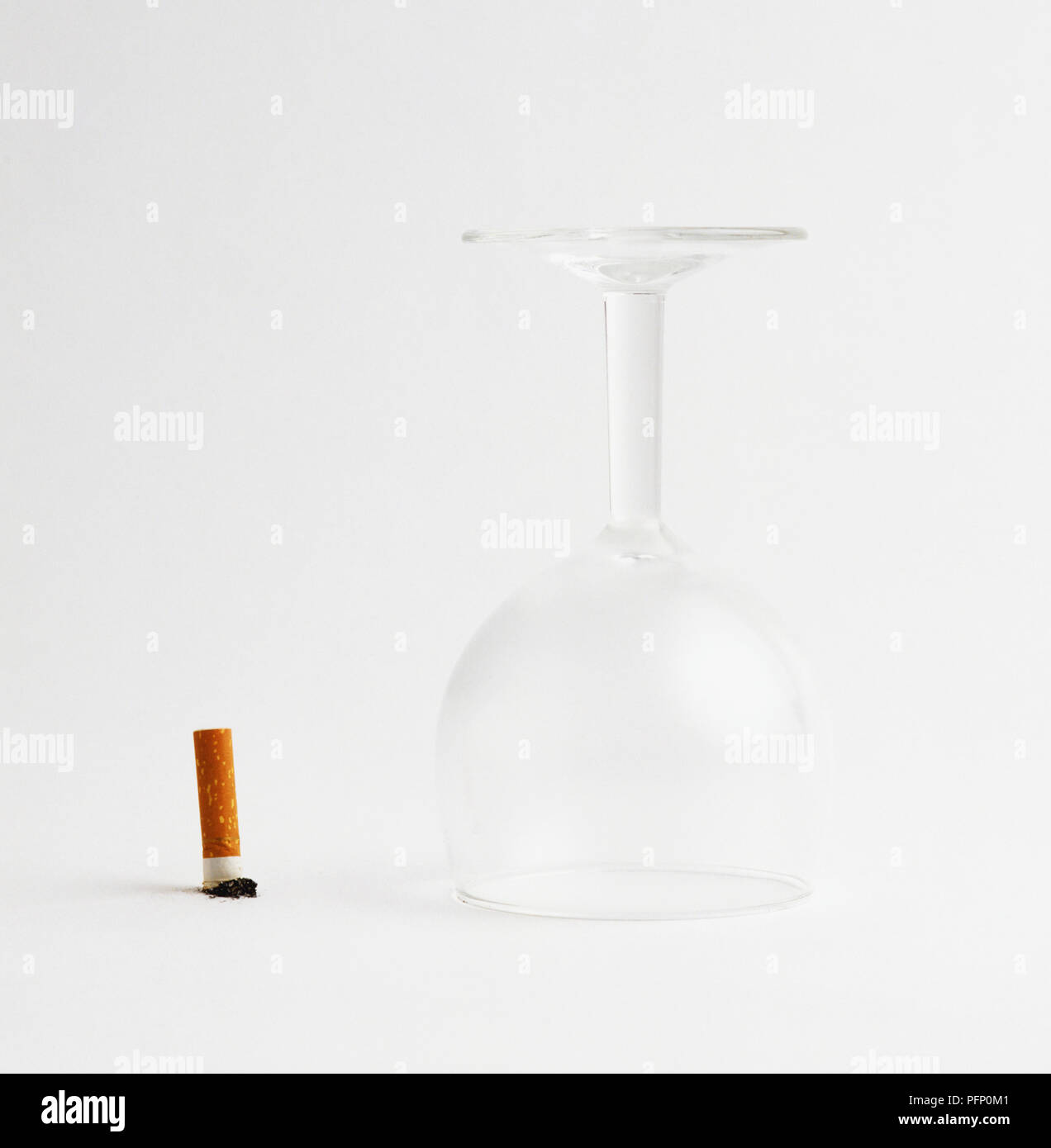A wine glass turned upside down and a stubbed out cigarette Stock Photo ...