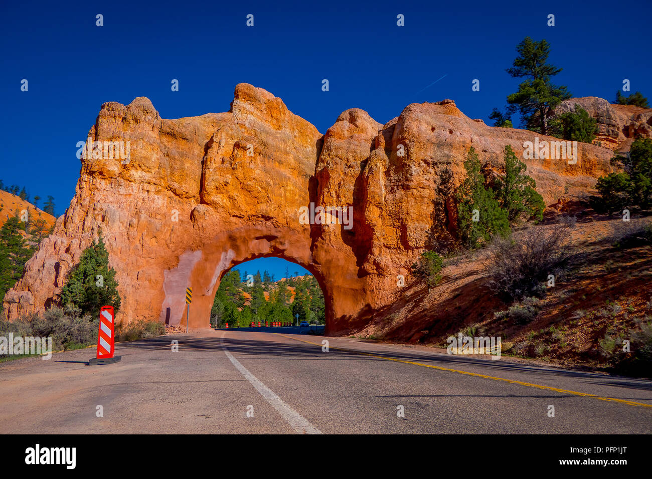 Scenic view of stunning red sandstone natural bridge and asphalt road ...