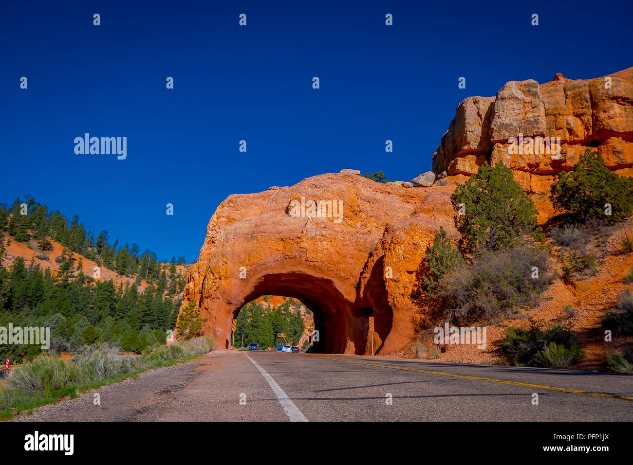 Scenic view of stunning red sandstone natural bridge and asphalt road ...