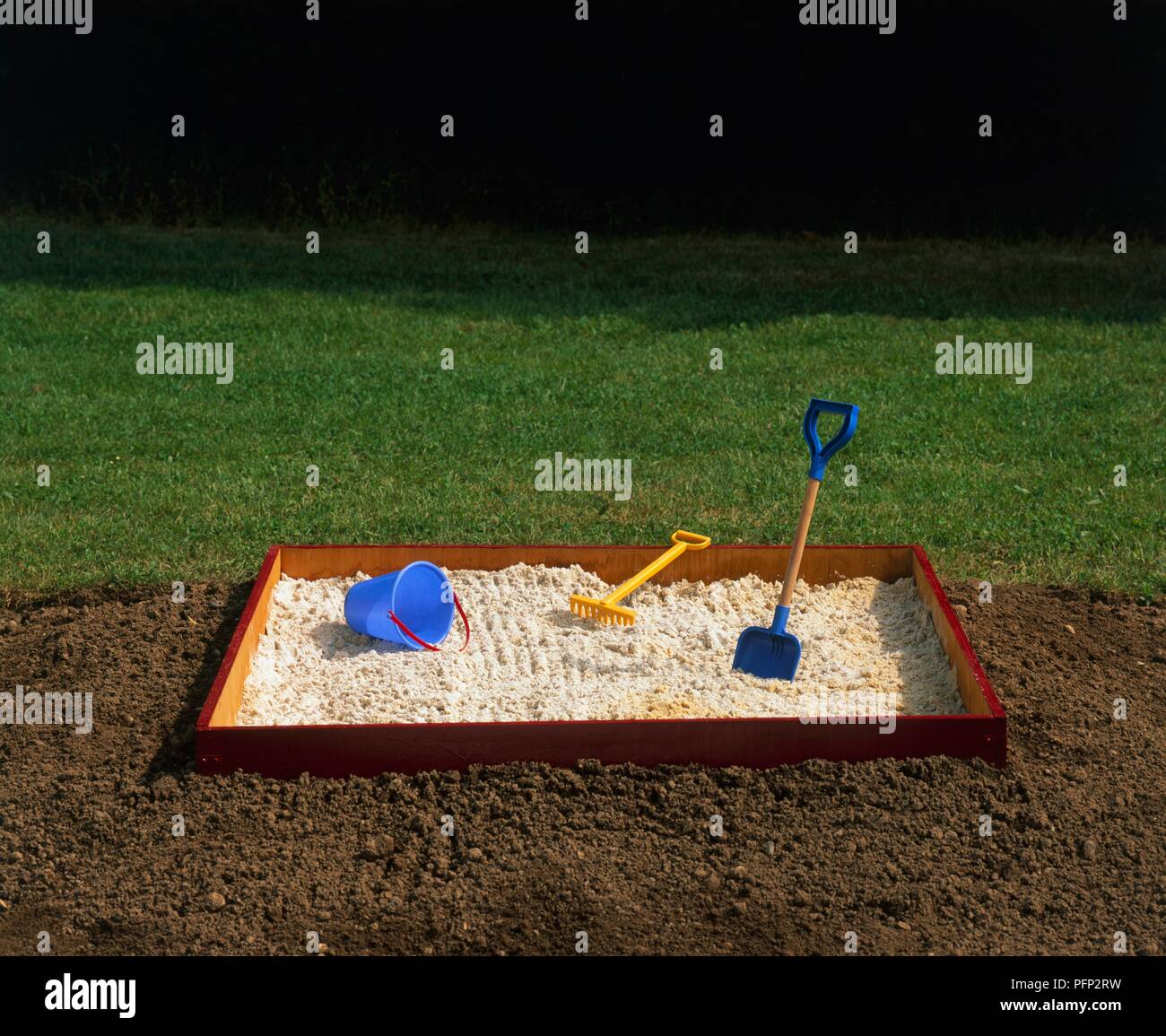 Bucket, spade and rake in children's sand pit Stock Photo - Alamy