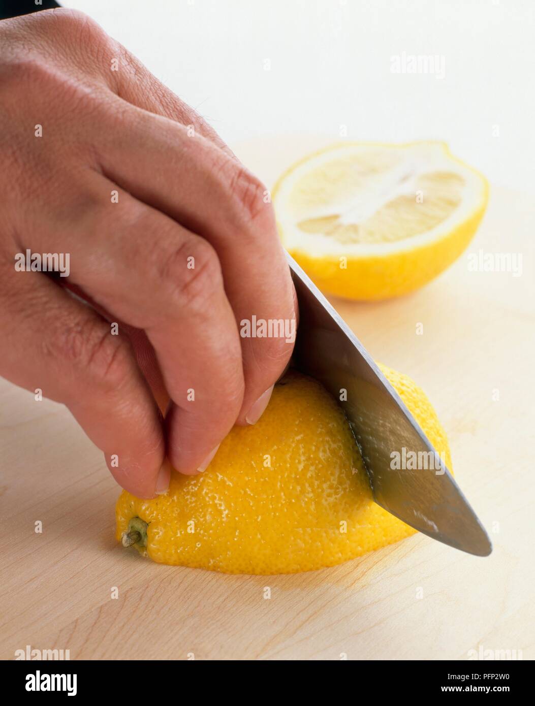 Hand shown slicing a lemon with a sharp knife, close-up Stock Photo - Alamy