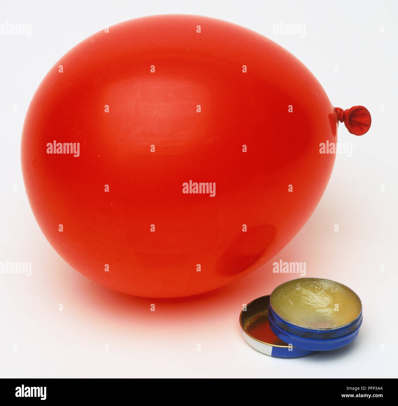 Inflated red balloon and tin of petroleum jelly Stock Photo - Alamy