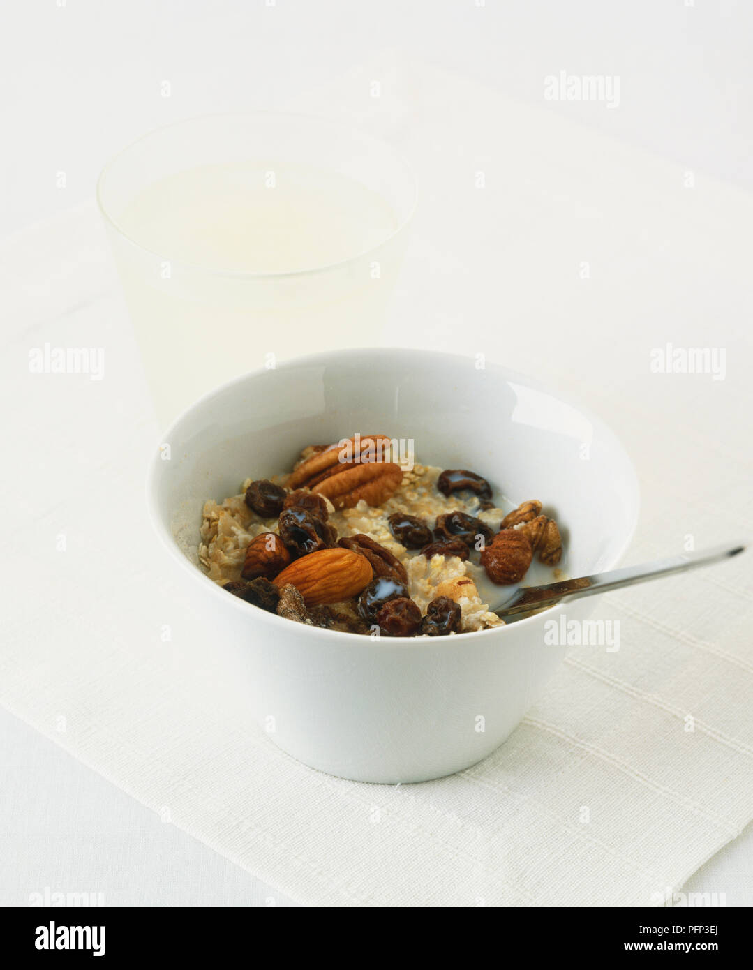Muesli served in white ceramic bowl with whole milk, accompanied by ...