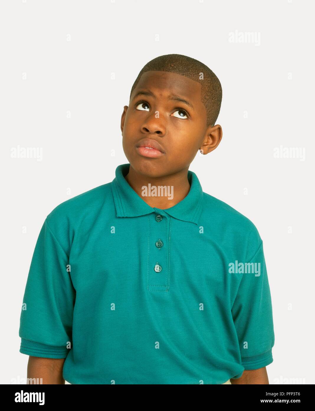 Boy in green polo-shirt looking up, front view Stock Photo - Alamy