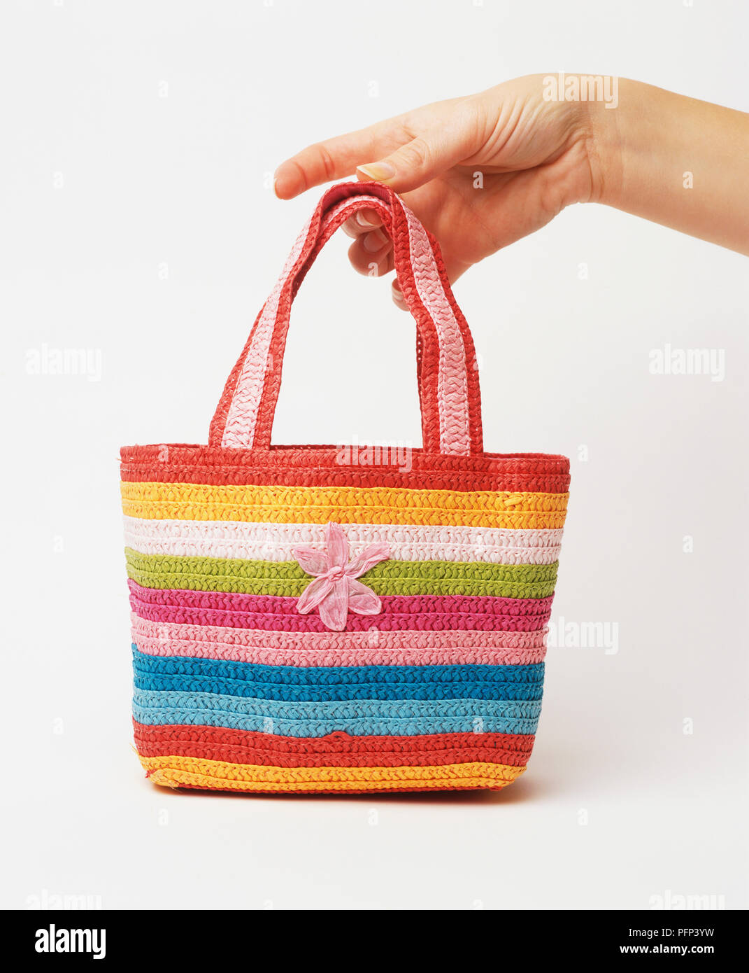 Hand holding straps of multi-coloured striped handbag Stock Photo - Alamy