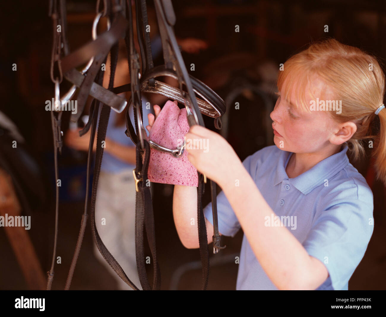 Young girl cleaning a bridle Stock Photo - Alamy