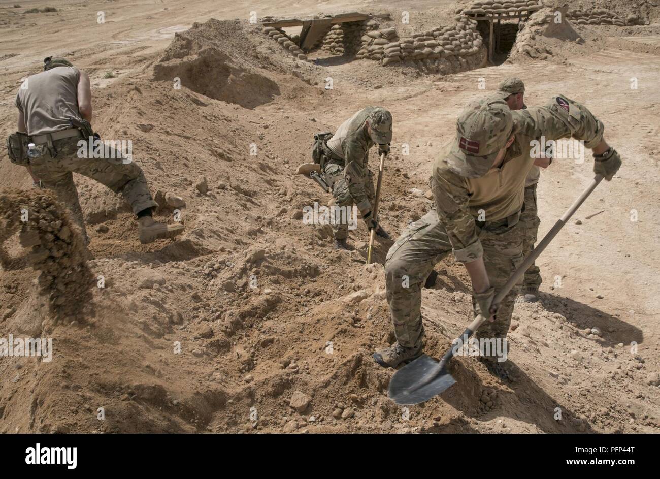 A Danish soldier operates a front end loader filled with sand to be ...