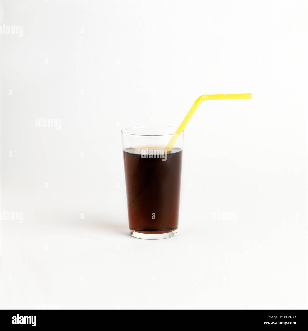 Cola drink in glass with yellow straw Stock Photo - Alamy