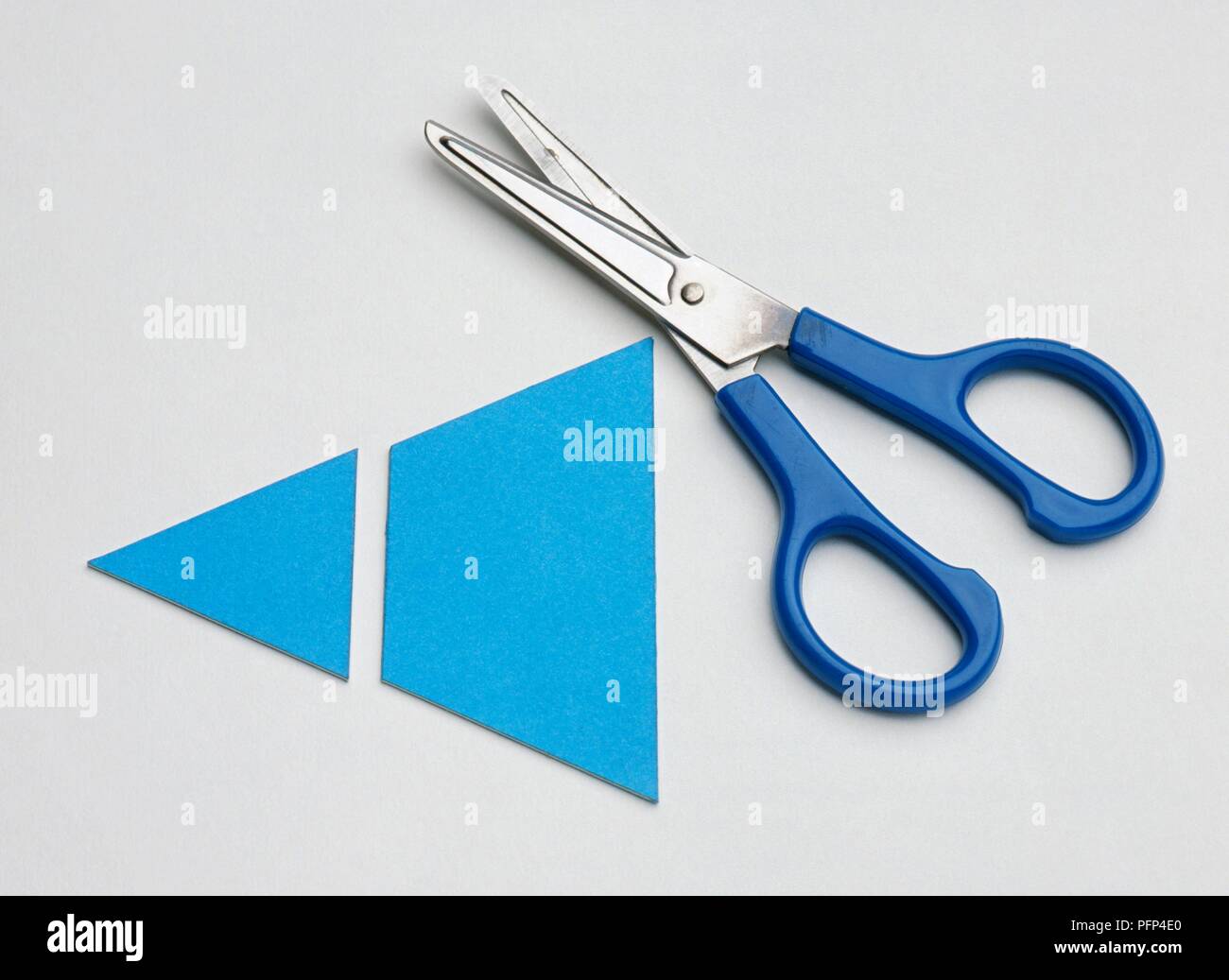 Blue paper triangle cut in half by blue scissors Stock Photo - Alamy