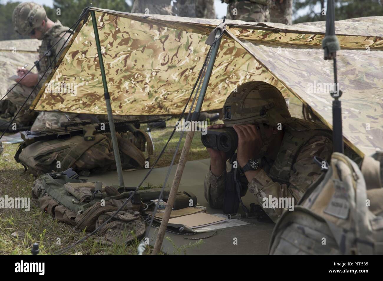 A British Army Commando looks downrange through binoculars during ...