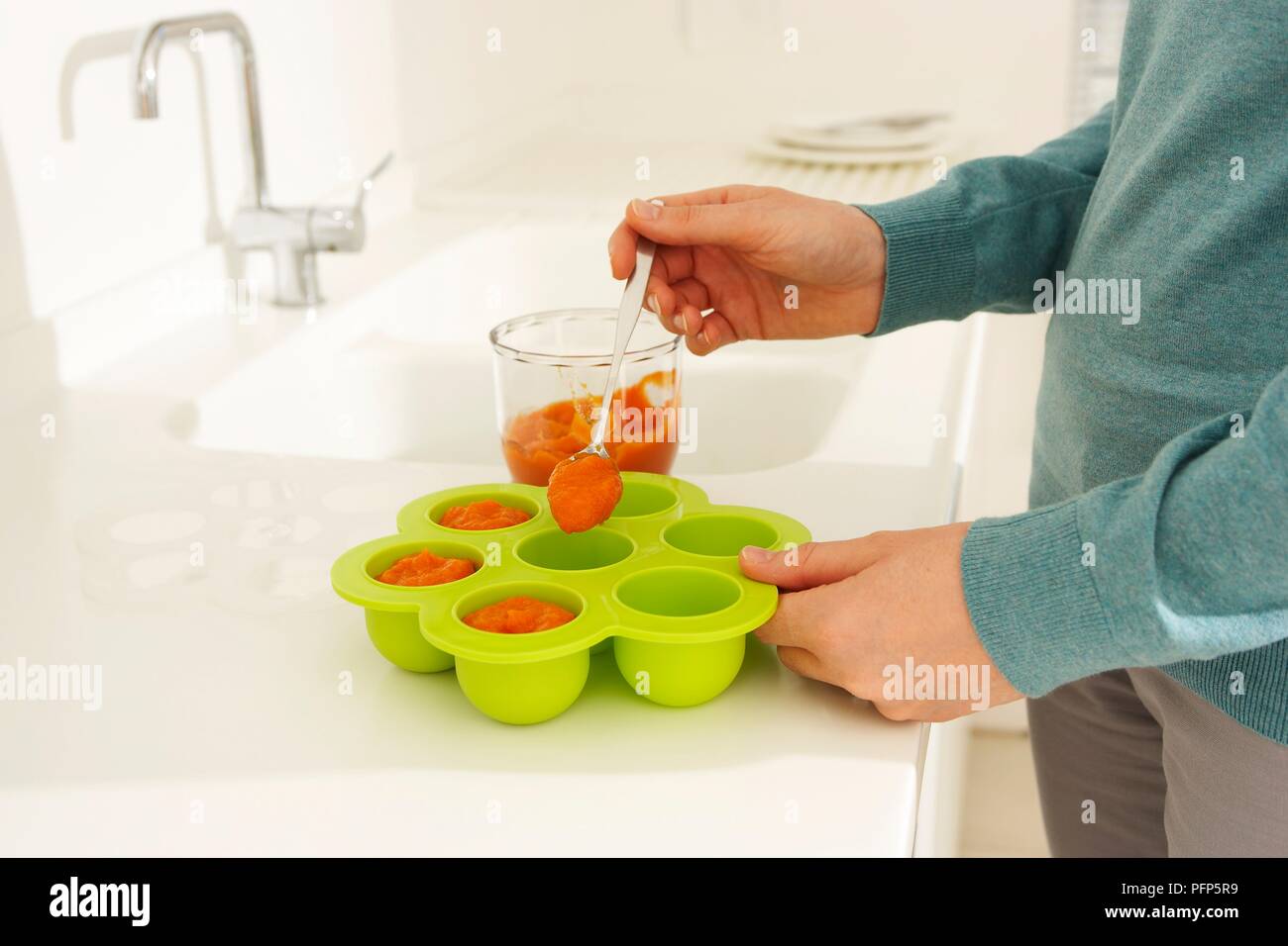 Woman spooning pureed baby food in tray for freezing, close-up Stock ...