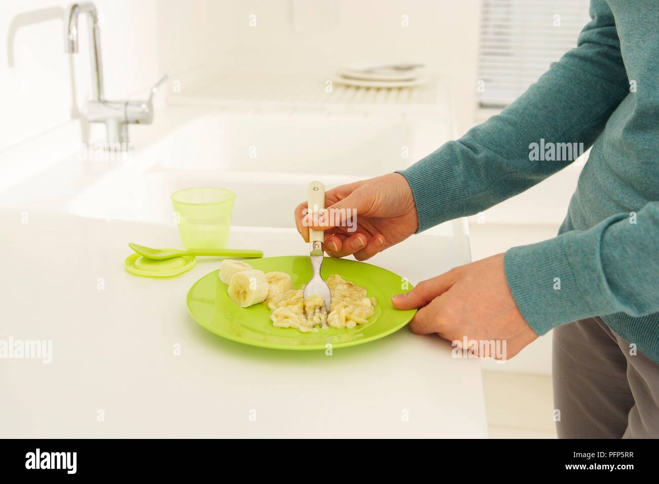 Woman mashing banana with a fork, close-up Stock Photo - Alamy