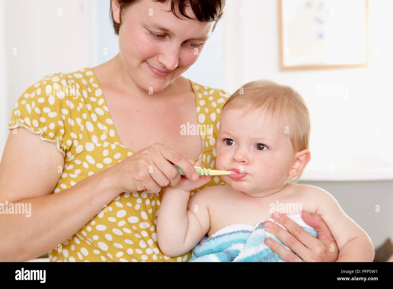 Woman helping baby boy clean his teeth, front view Stock Photo - Alamy