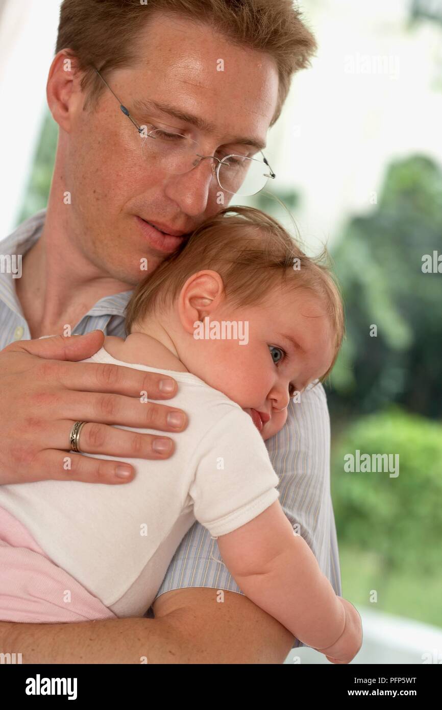 Man holding baby girl in his arms, one hand on her back, close-up Stock ...