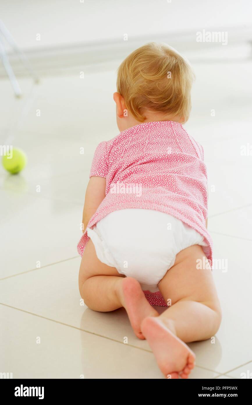 Baby girl on all fours on tiled floor, rear view Stock Photo - Alamy