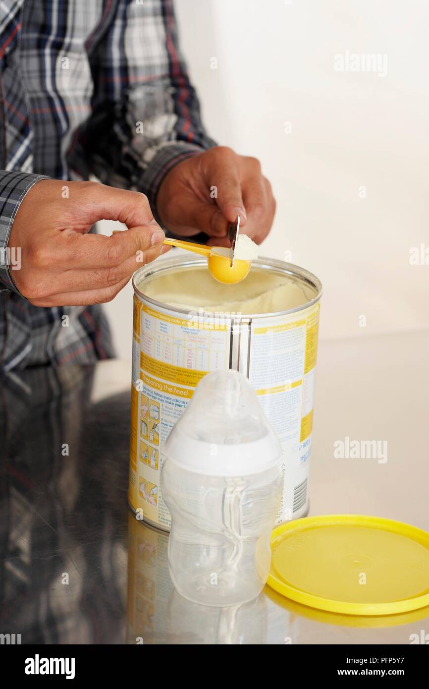Man scraping off excess formula milk from measuring spoon, close-up ...