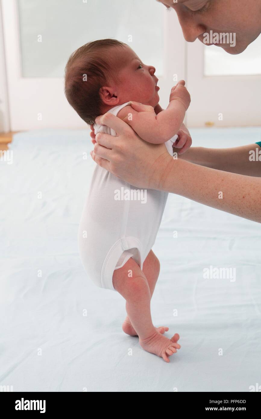 Woman picking up a young baby girl, side view Stock Photo - Alamy