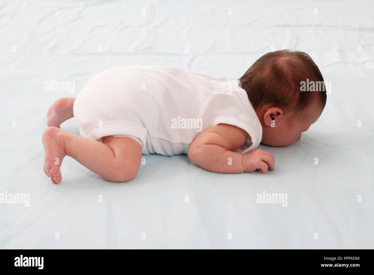 Baby girl lying on her front, side view Stock Photo - Alamy