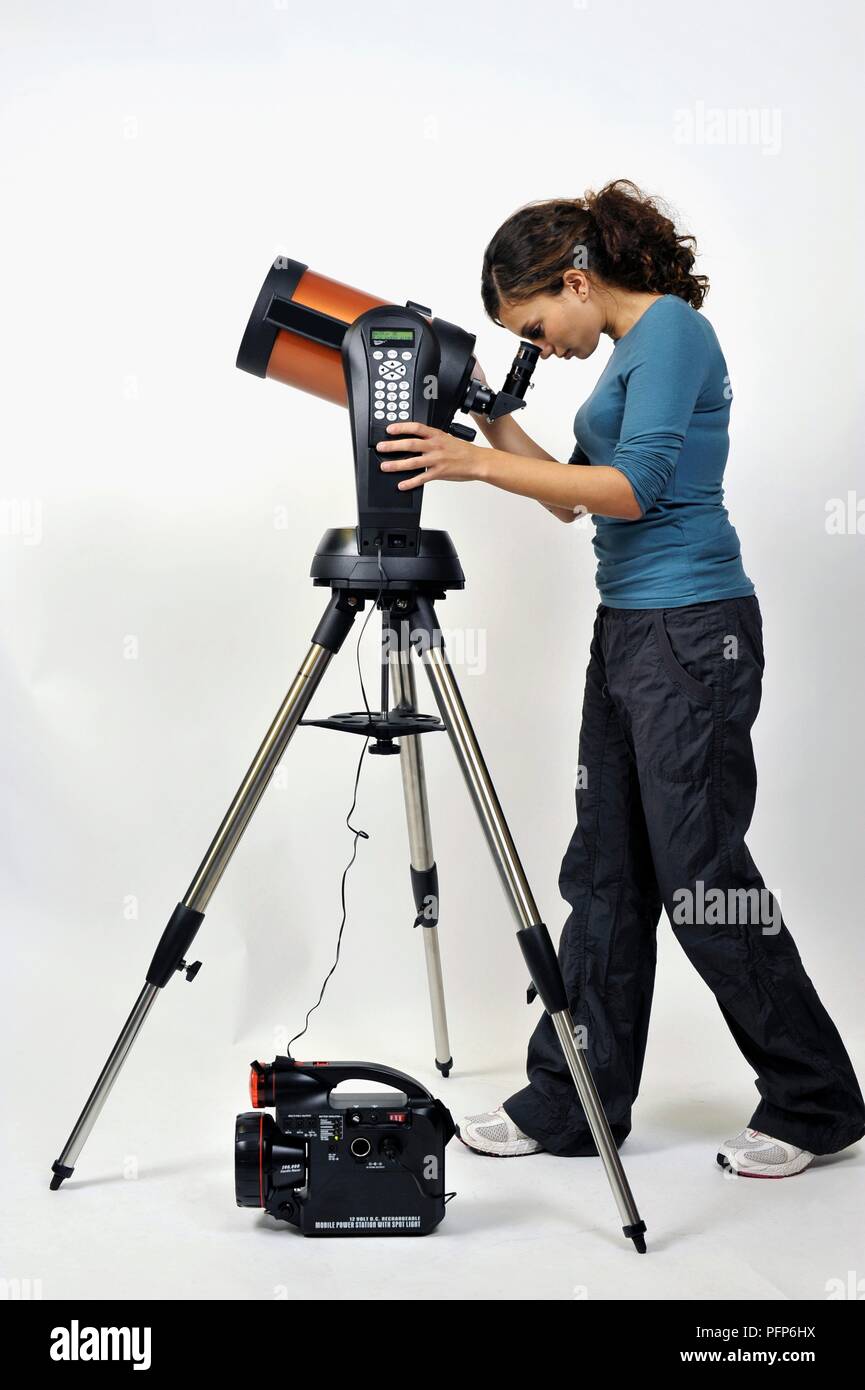 Woman looking through eyepiece on astronomical telescope, side view ...