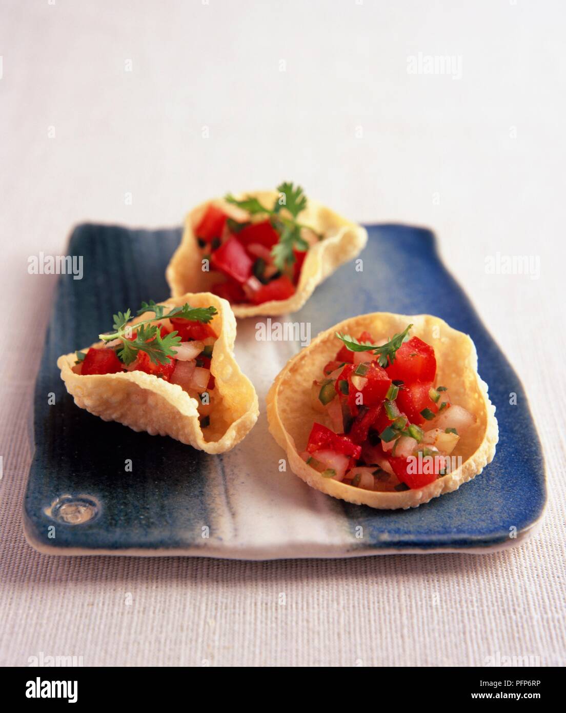 Masala popadums with tomato, green chilli, and coriander leaves, on ...