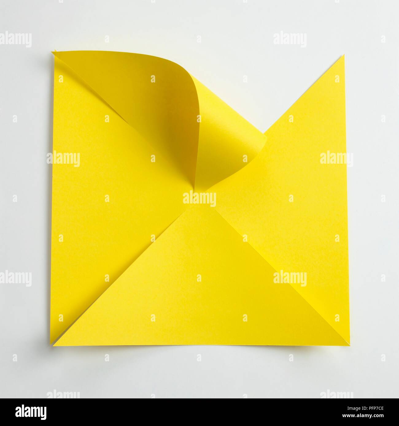 Square yellow paper cut into triangle shapes, one corner folded over ...