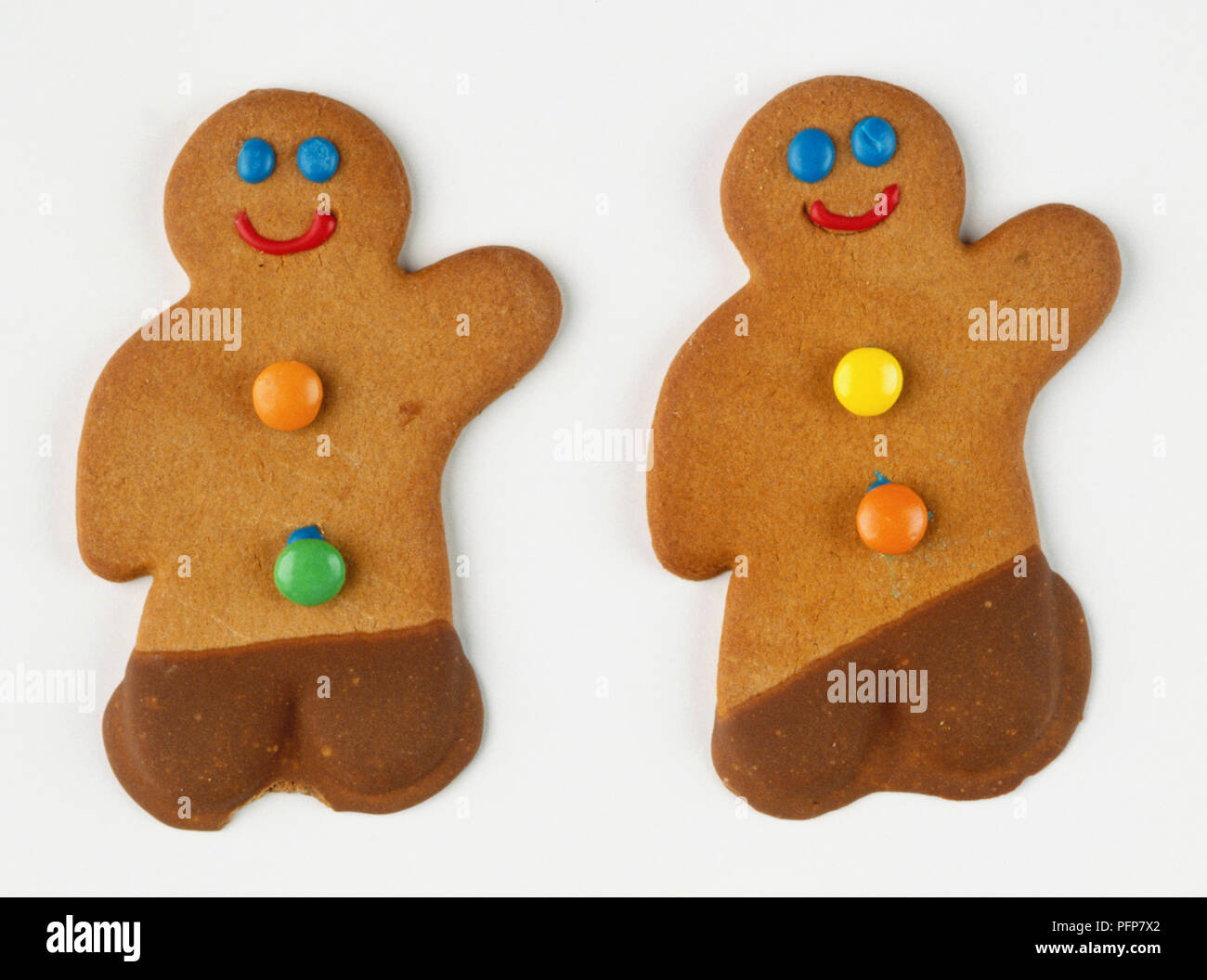 Two gingerbread men, dipped in chocolate and decorated with multi ...