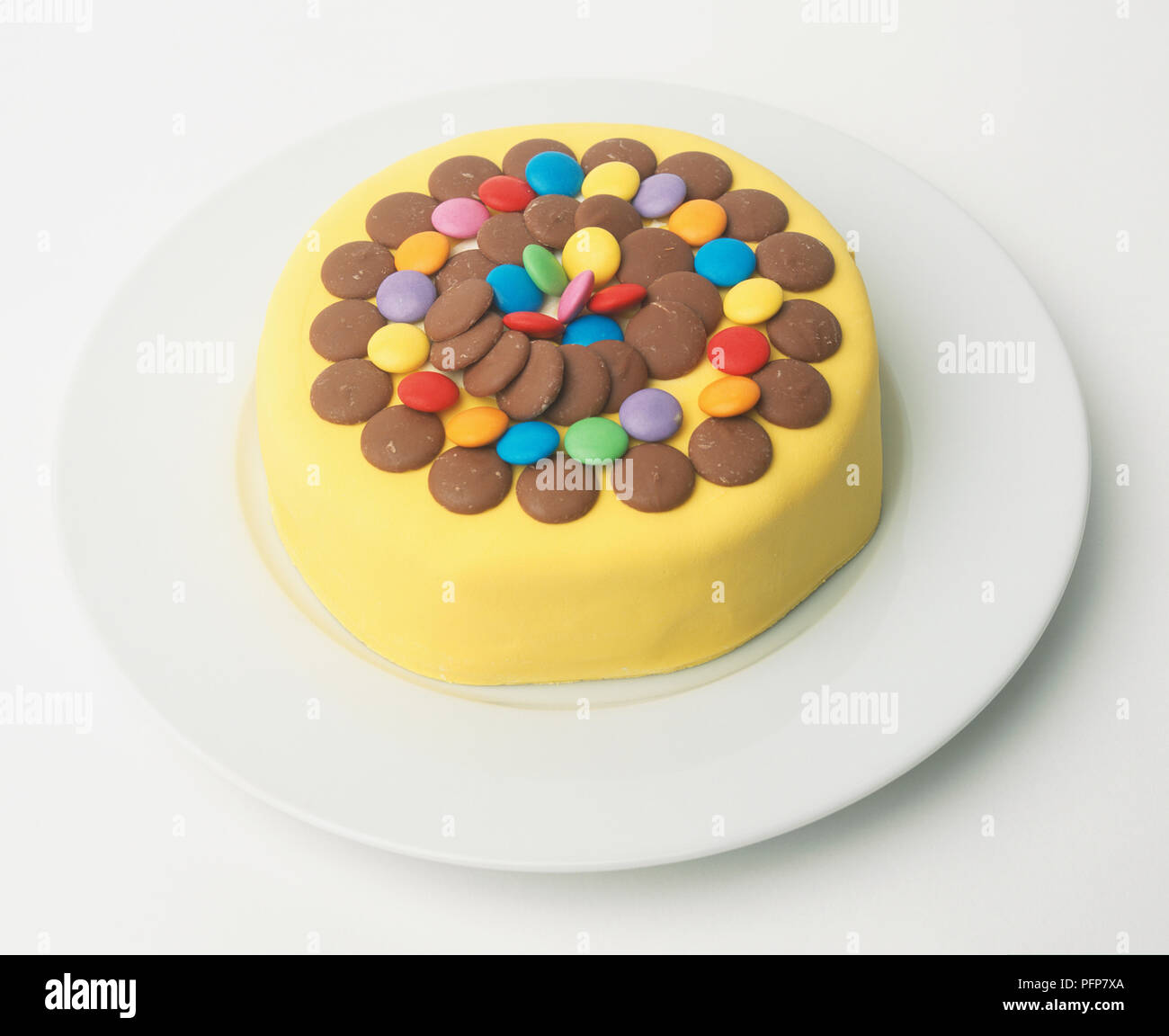 Yellow iced cake decorated with multicoloured sugar sweets and ...