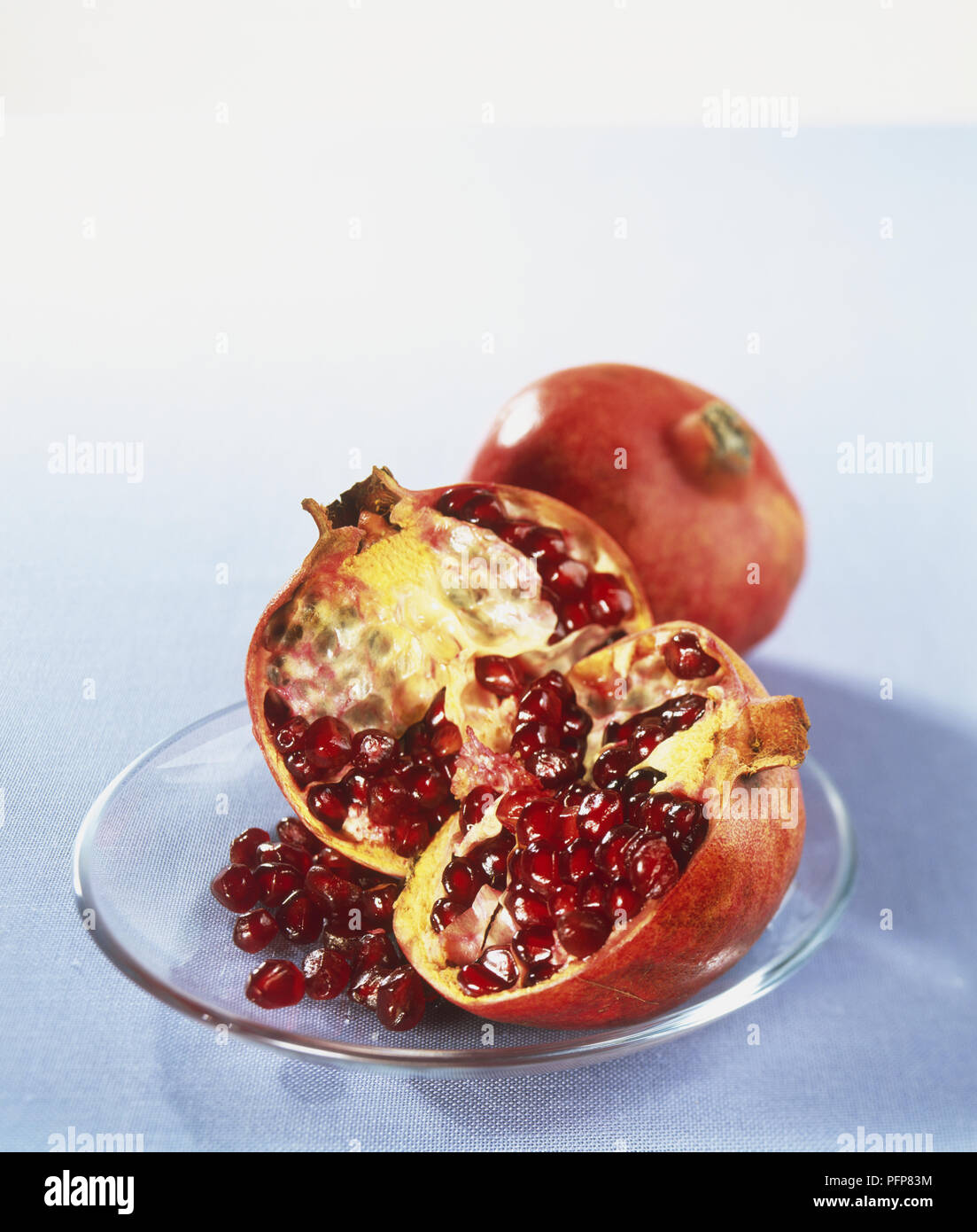 Punica granatum, Pomegranate broken in half revealing red seed clusters ...