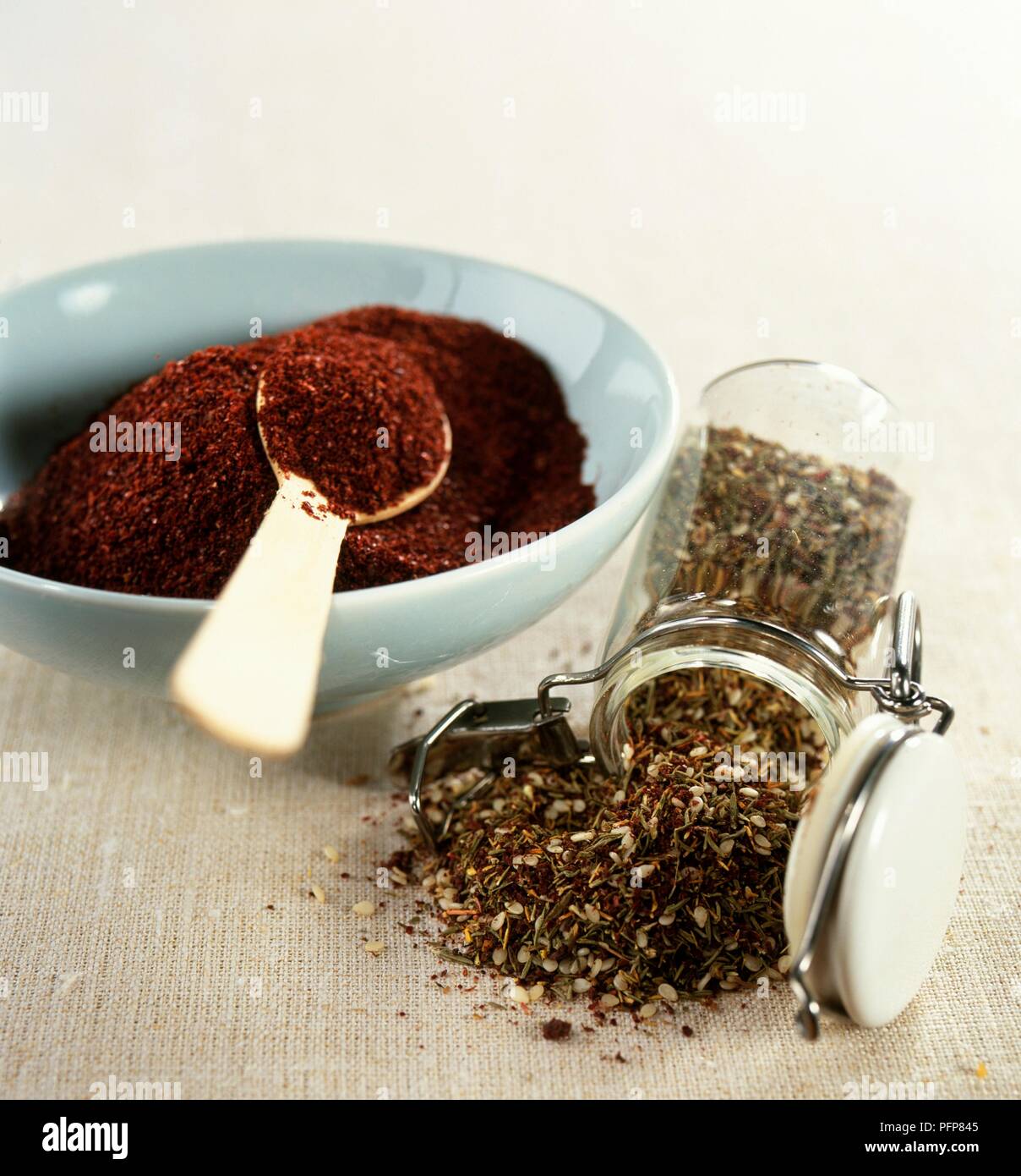 Dried and ground sumac in bowl and crushed seeds spilling from ...
