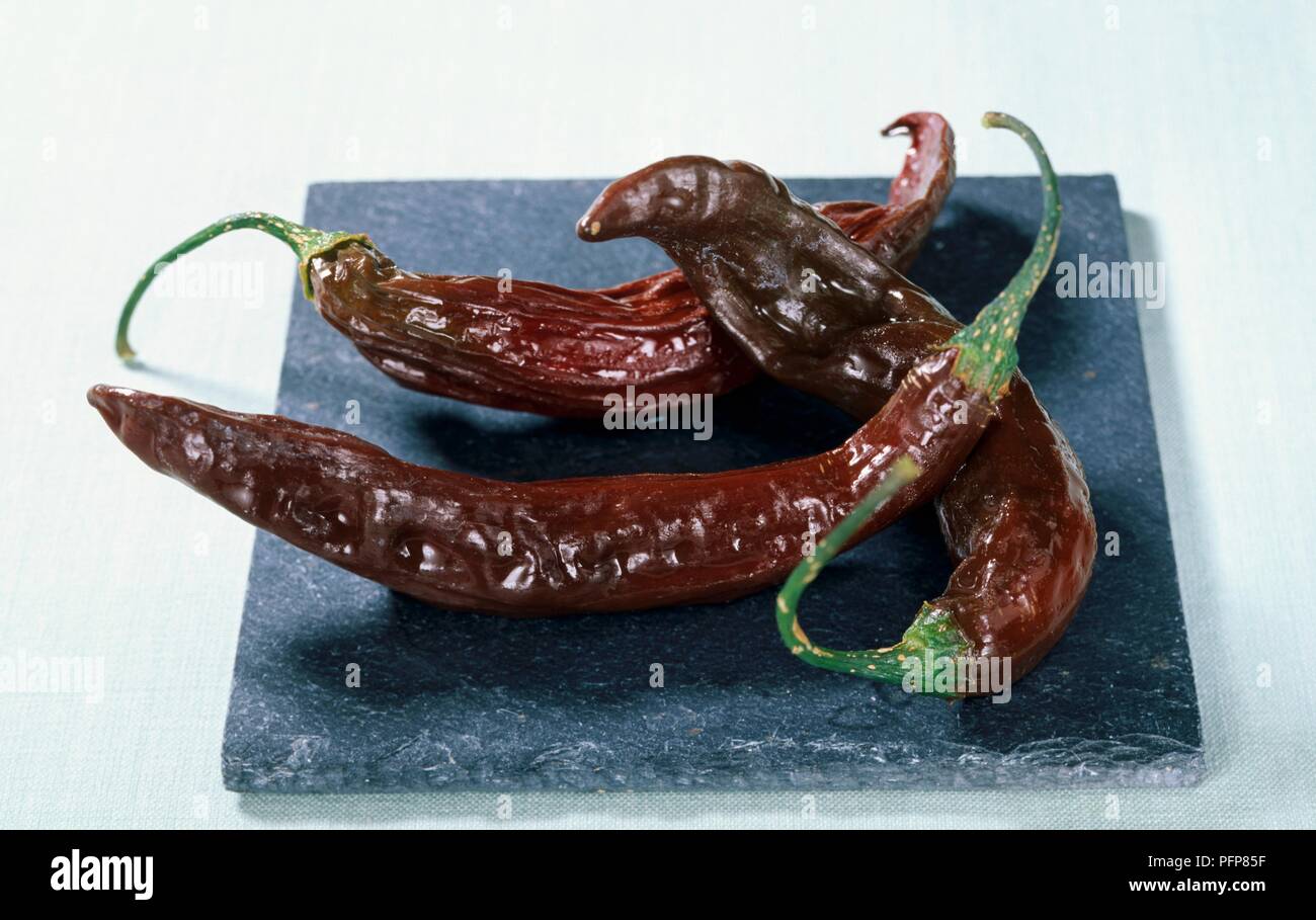 Dried Pasilla (Capsicum annuum) chilli pepper on black tile Stock Photo ...