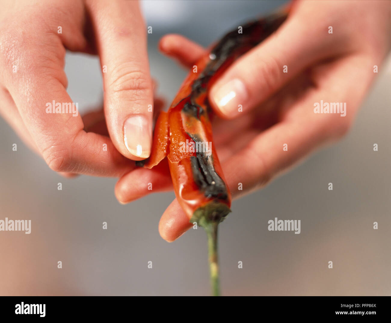 Using fingers to peel skin from charred red chilli pepper, close-up ...