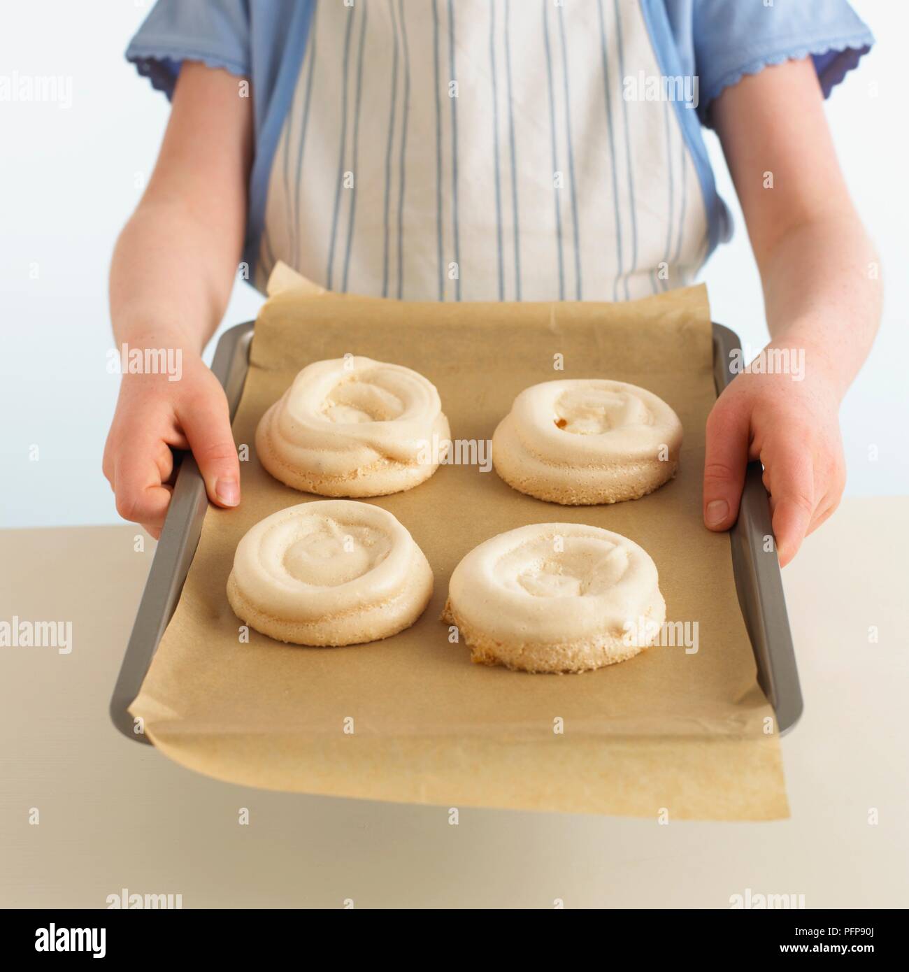 Girl holding baked meringues on baking tray Stock Photo - Alamy